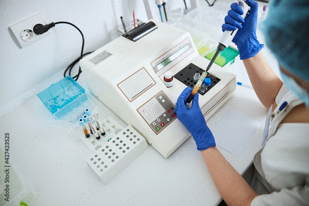 Lab worker conducting a coagulation test using an automated pipette ...