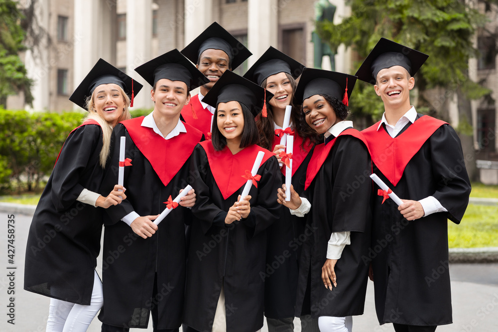 Cheerful multiracial students celebrating graduation, smiling at camera ...