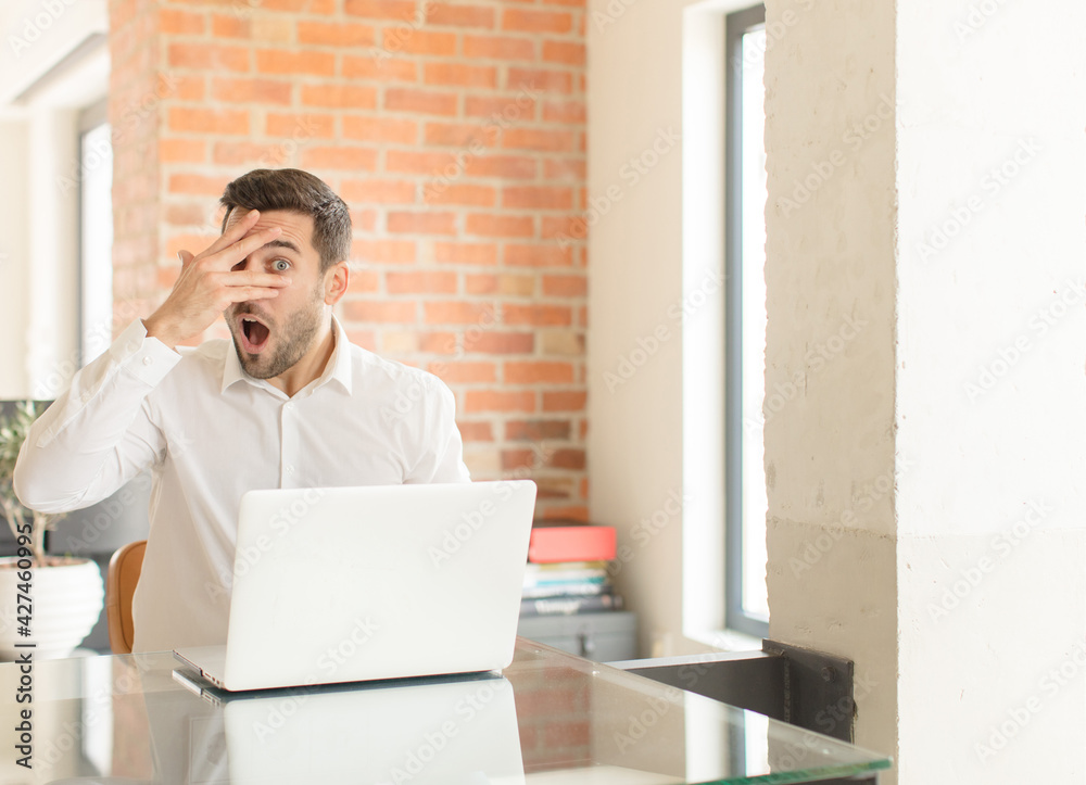 handsome businessman looking shocked, scared or terrified, covering ...