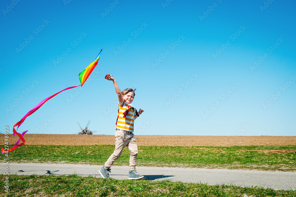 Happy family on summer walk. Young boy flies his kite in an open field ...