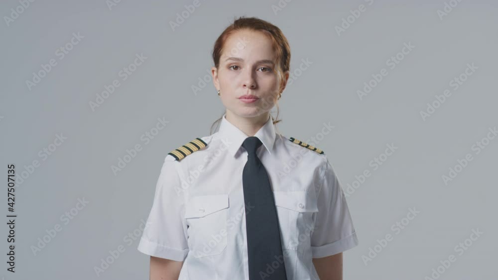 Serious young female airline pilot or ship captain wearing uniform in ...