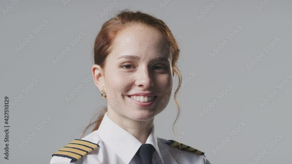 Smiling young female airline pilot or ship captain wearing uniform in ...