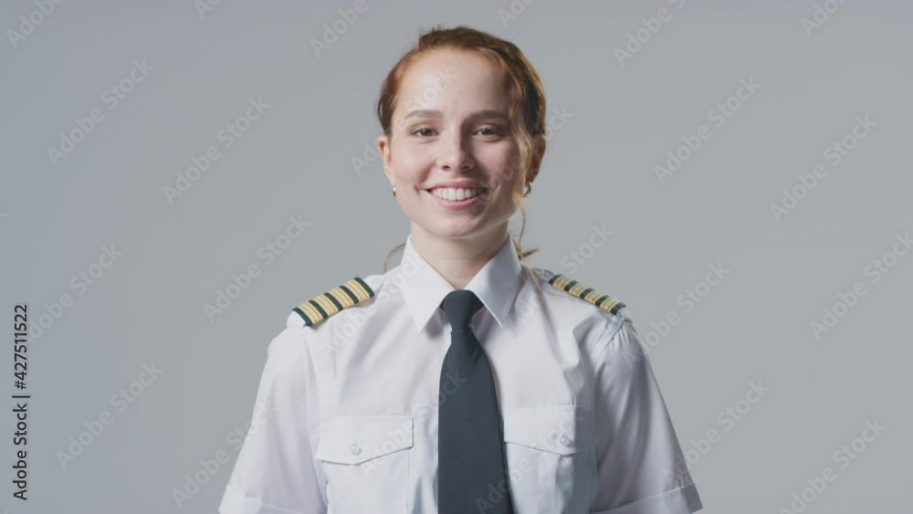 Smiling young female airline pilot or ship captain wearing uniform in ...