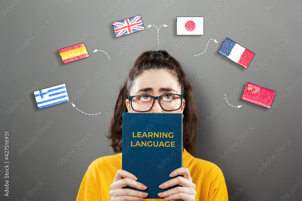 A portrait of a young thoughtful woman in glasses holding a textbook ...