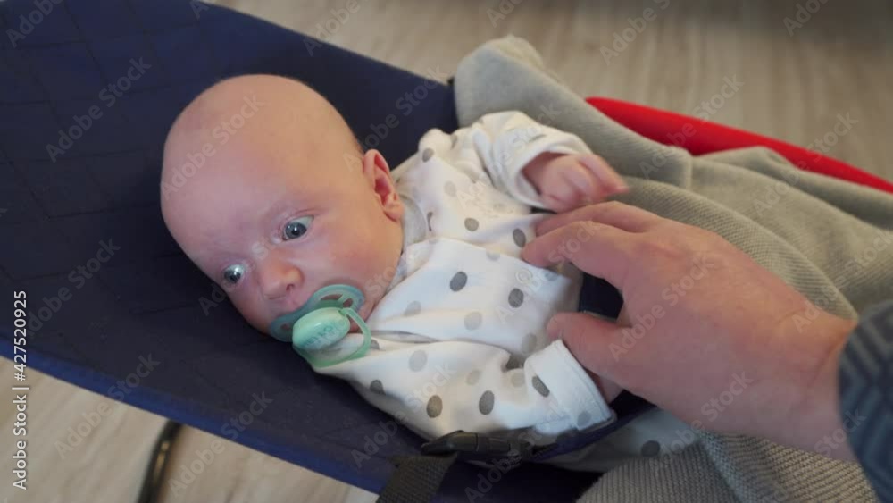 Hands of a father rocking his baby boy in baby bouncer, 1 month old ...