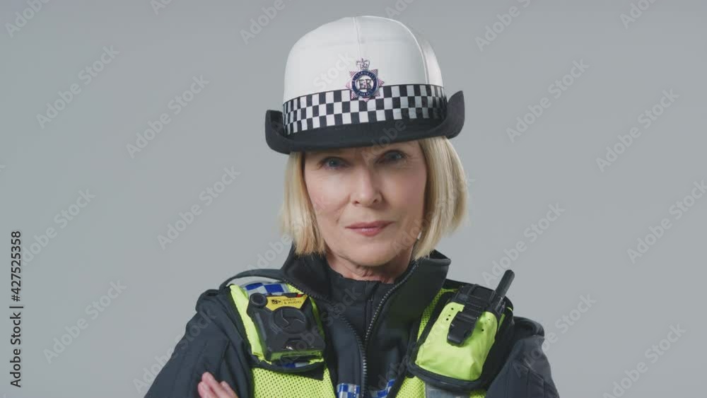 Serious mature female police office wearing uniform in front of plain ...