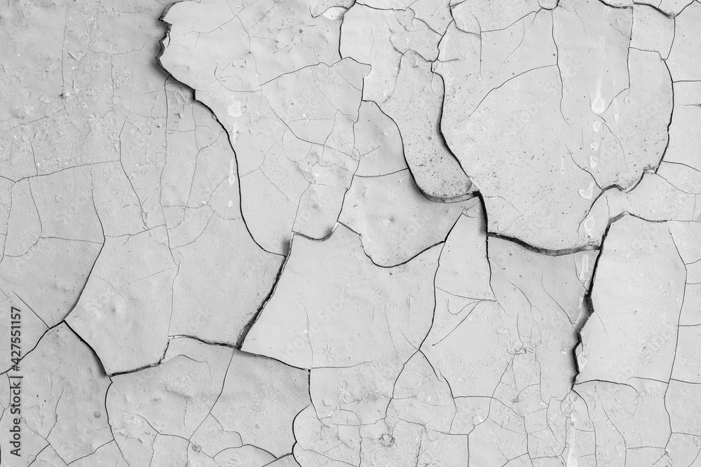 White peeling paint on the wall. Old concrete wall with cracked flaking paint. Weathered rough ...