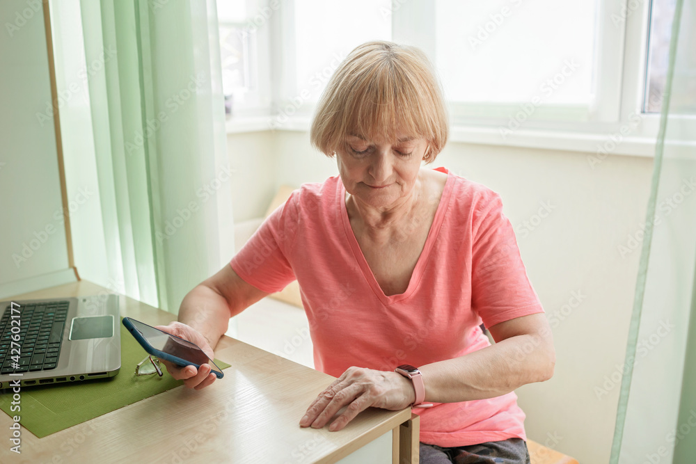 Senior woman checking health information using smart watch and mobile ...