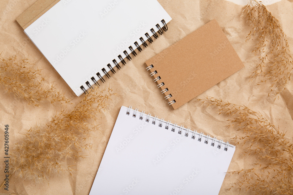 blank notebooks with white paper and dry pampas grass on crumpled brown ...