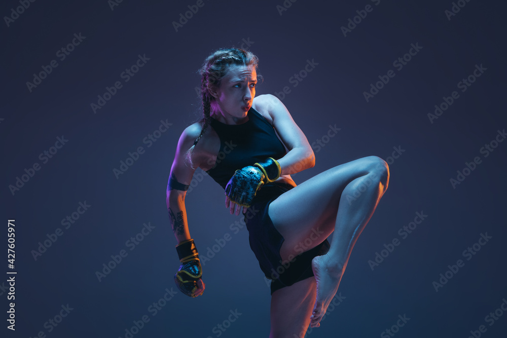Young female MMA fighter posing isolated over blue background in neon ...