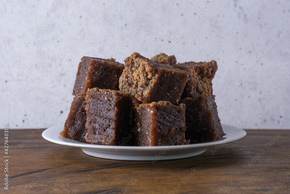 plate of dodol on a wooden table, also called kalu dodol, sri lankan ...