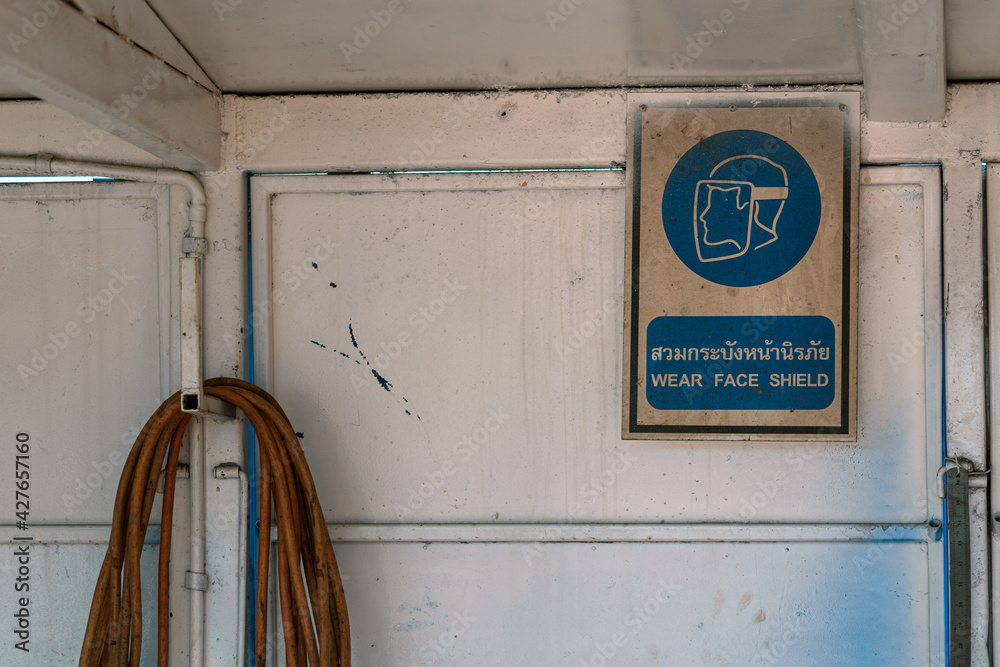 "Wear face shield" warning sign which is installed on welding workshop ...