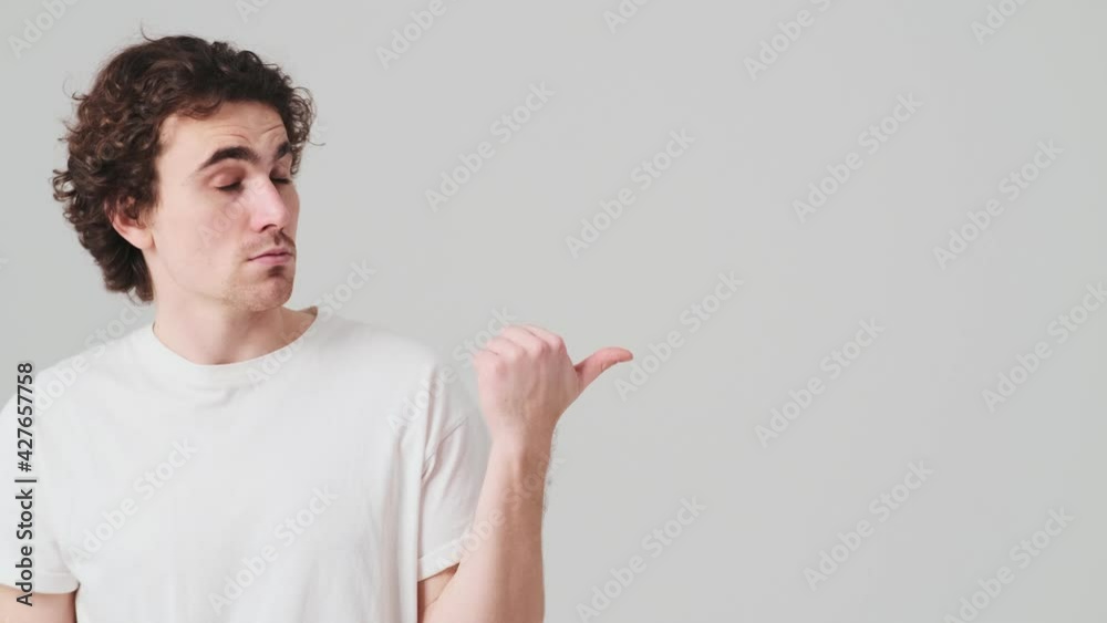 A man with curly hair showing his thumb up to the side and pressing his ...