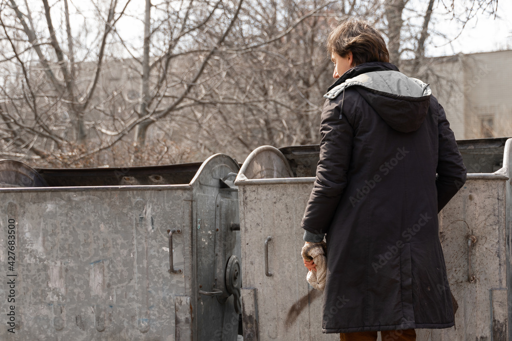 homeless guy looking for food in garbage cans on the street. poverty ...