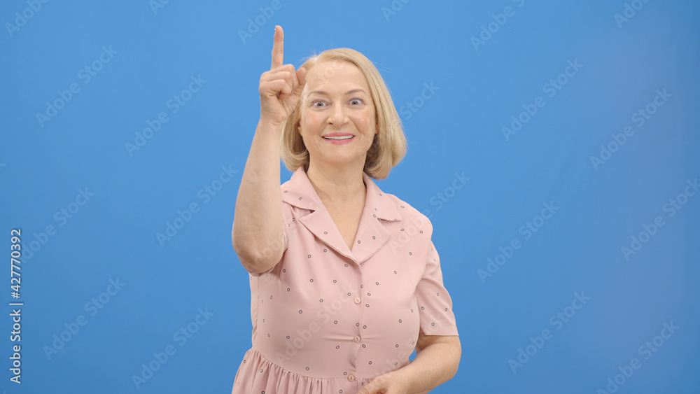 Cheerful amusing old lady is pointing in the ad space above the screen ...