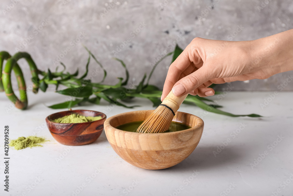 Woman preparing matcha tea on light background Stock Photo | Adobe Stock