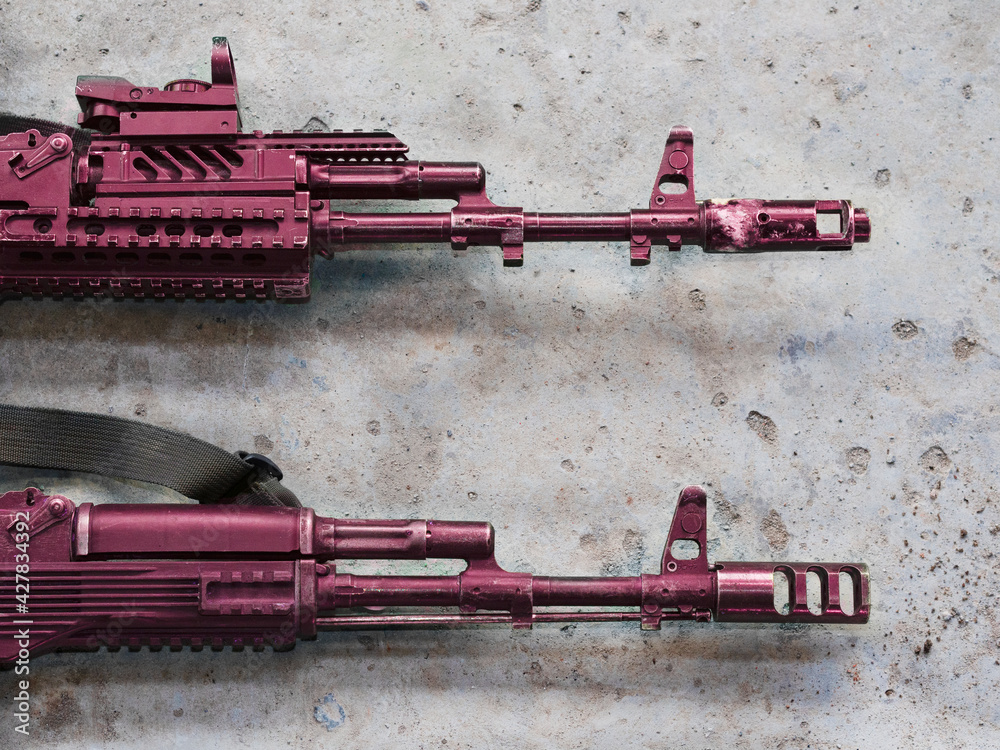 Two custom pink assault rifles close-up lying on the concrete floor top ...