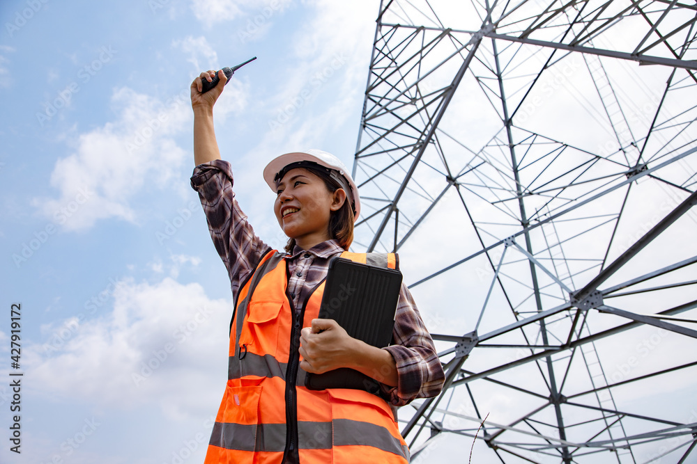 Electrical Asian beautiful engineer with high voltage electricity pylon ...