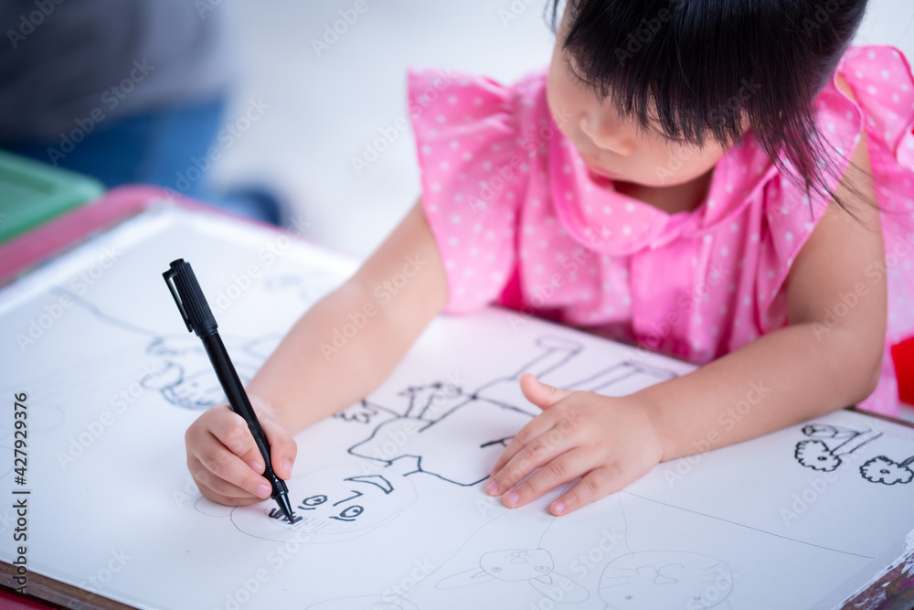 Selective focus at child hand holding magic pen. Asian cute girl doing ...
