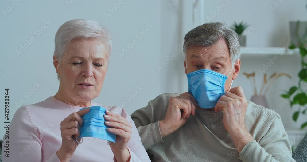 Elderly couple talking wearing medical masks on their old faces ...