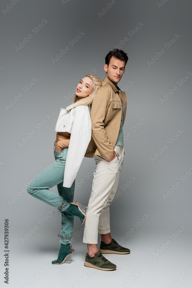 full length of trendy models standing back to back while posing with ...