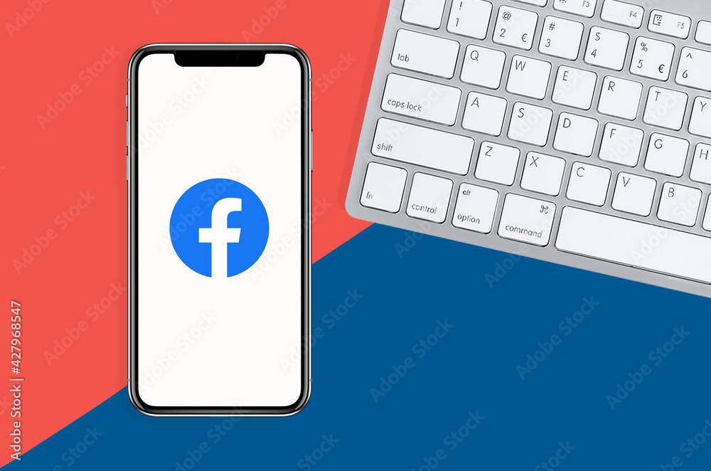 Facebook logo app on a smartphone screen, wooden desk background with ...