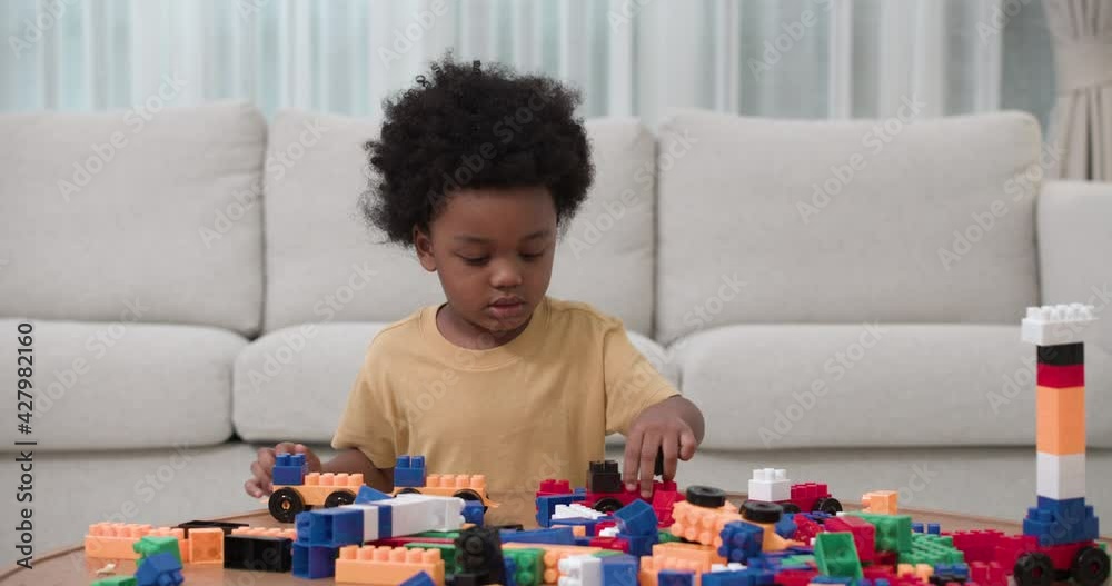A little adorable cute African American boy making a train and the city ...
