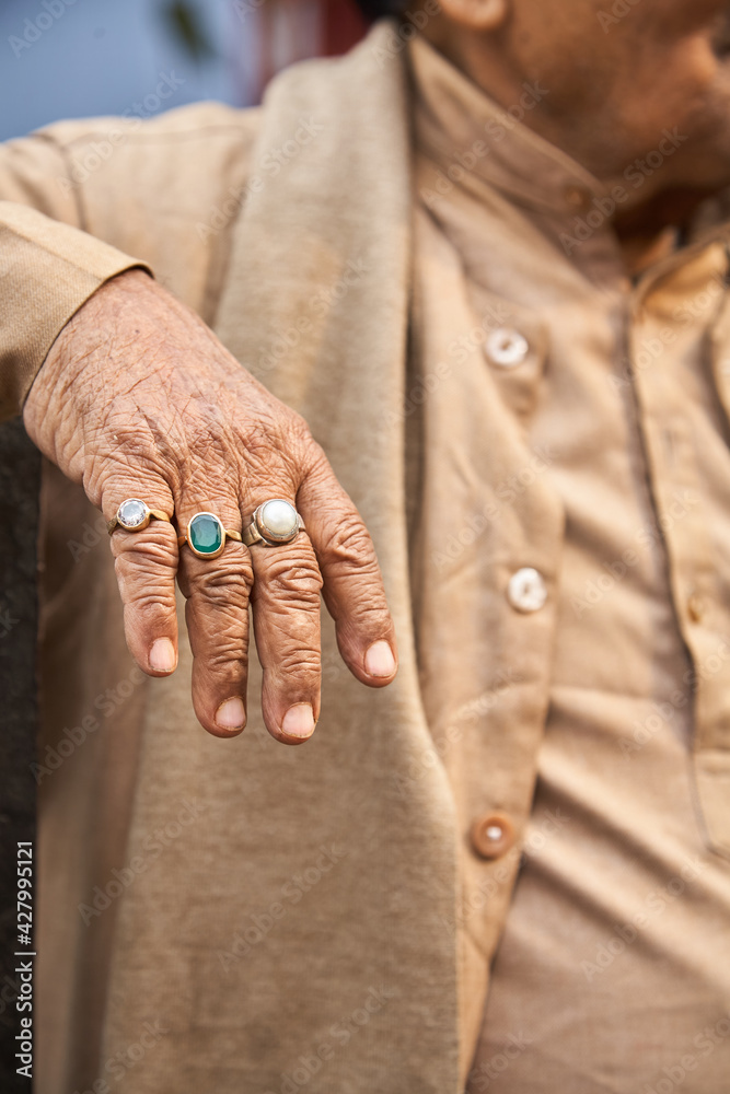 Old Indian man hand with many rings. Head is not visible. Here someone ...
