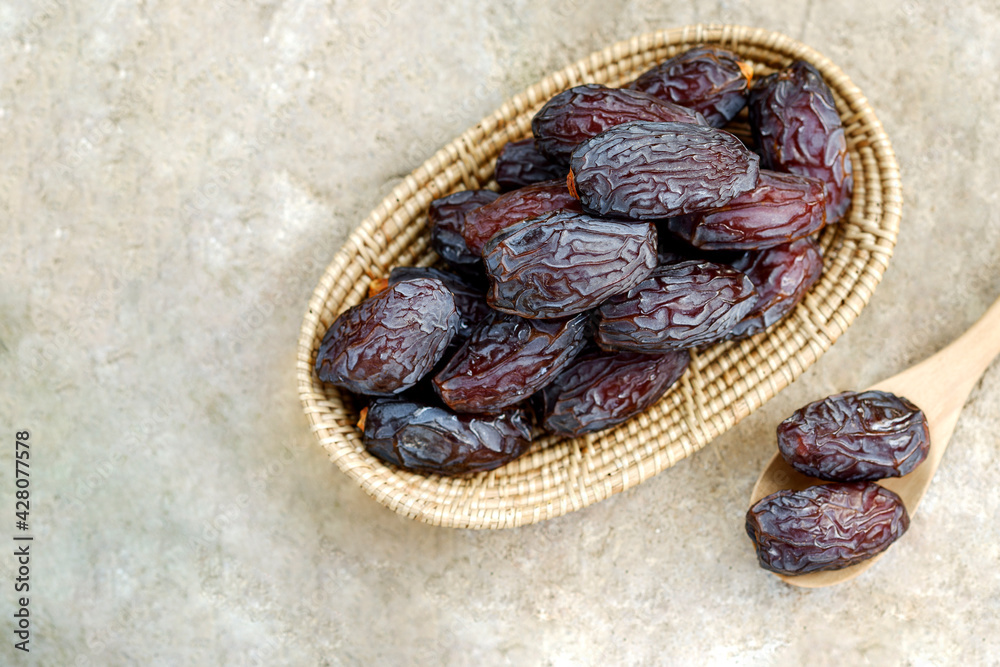 The large date palms (Medjool) in cups and wooden spoons with a cement ...