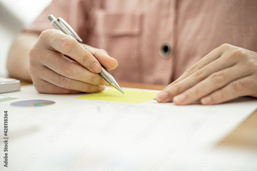 A businesswoman is taking notes on a note on a company financial ...