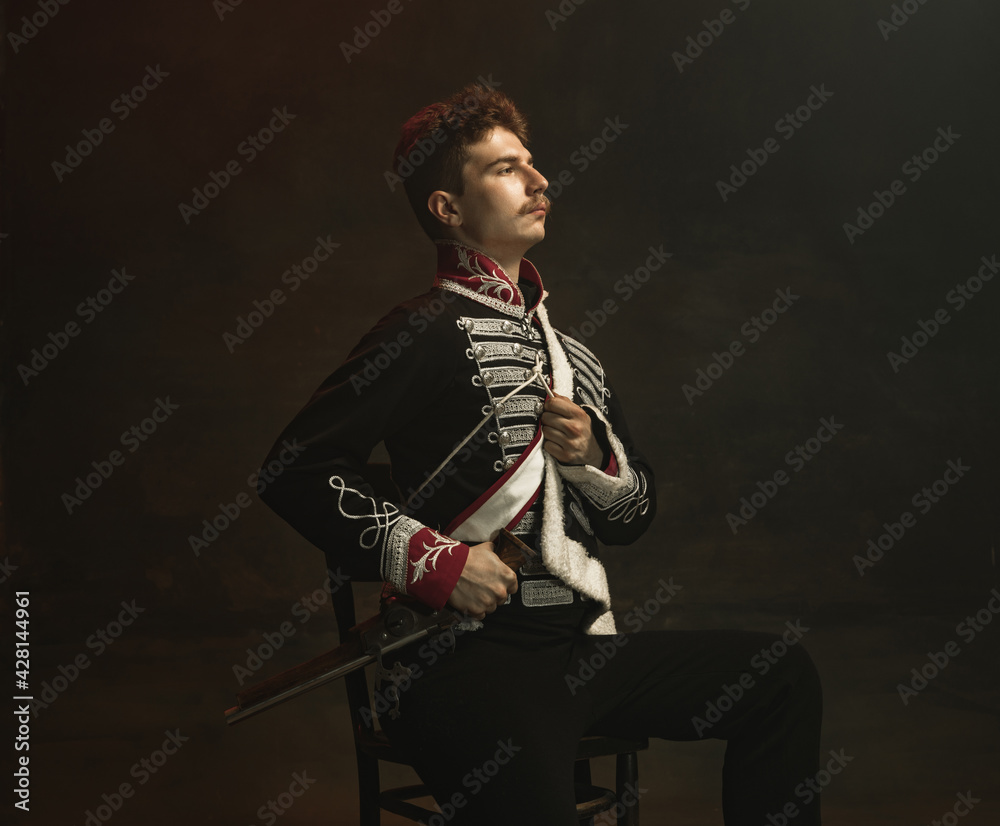 Young man in suit as royal person isolated on dark green background ...