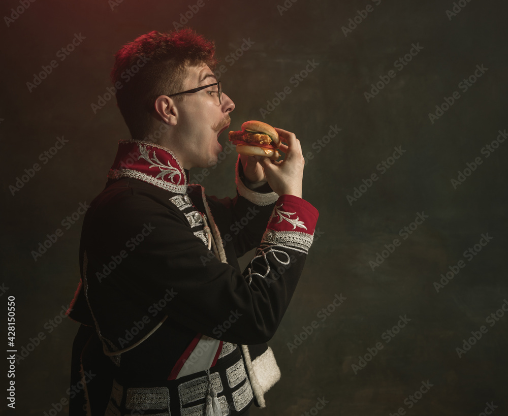 Young man in suit as royal person isolated on dark green background ...