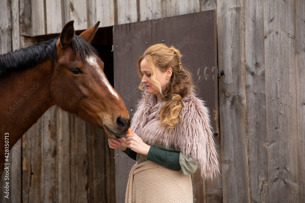 Eine blonde Frau aus den Mittelalten Zeiten kuschelt mit ihrem Pferd ...