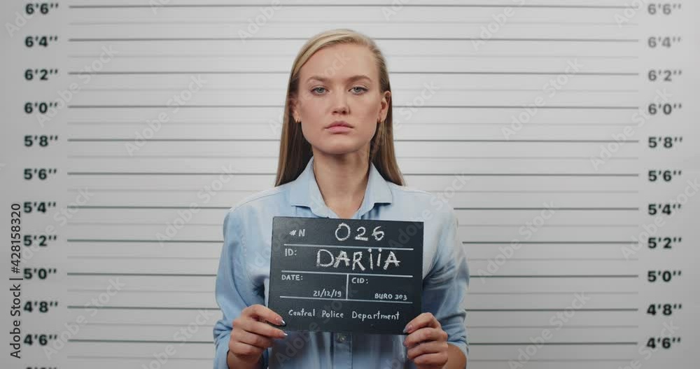 Mugshot of beautiful arrested woman holding sign for photo in police ...