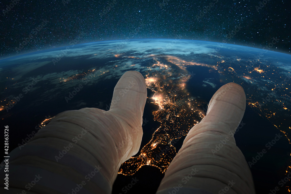 Spaceman sits and looks at the blue planet earth with night lights of ...