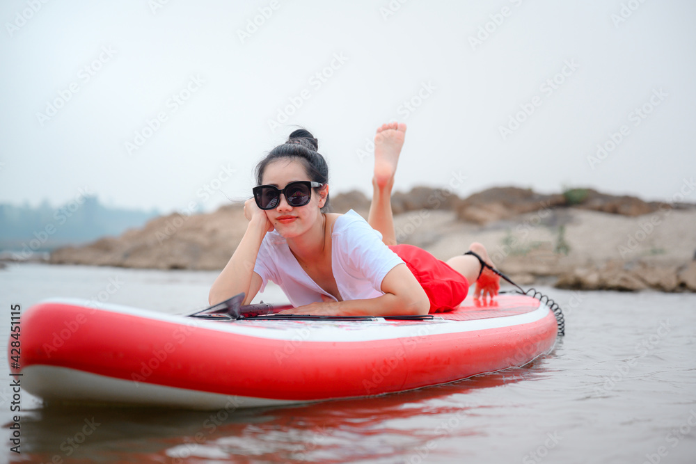 Beautiful Asian girl on a paddleboard Lay paddling in the ocean on the ...
