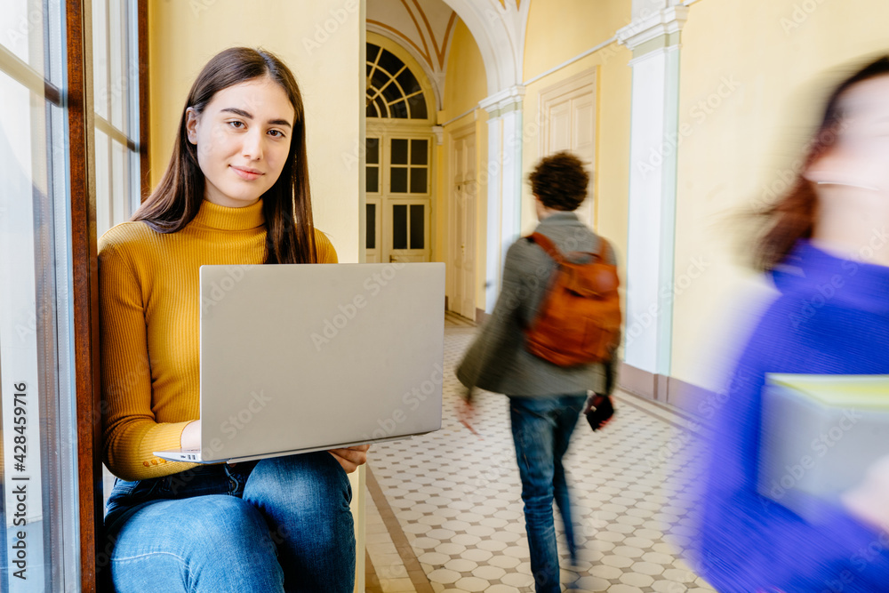 Hipster female student in yellow sweater working with laptop with ...