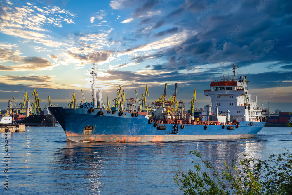 Empty cargo ship leaves port. Blue cargo ship on a sky background. Lots ...