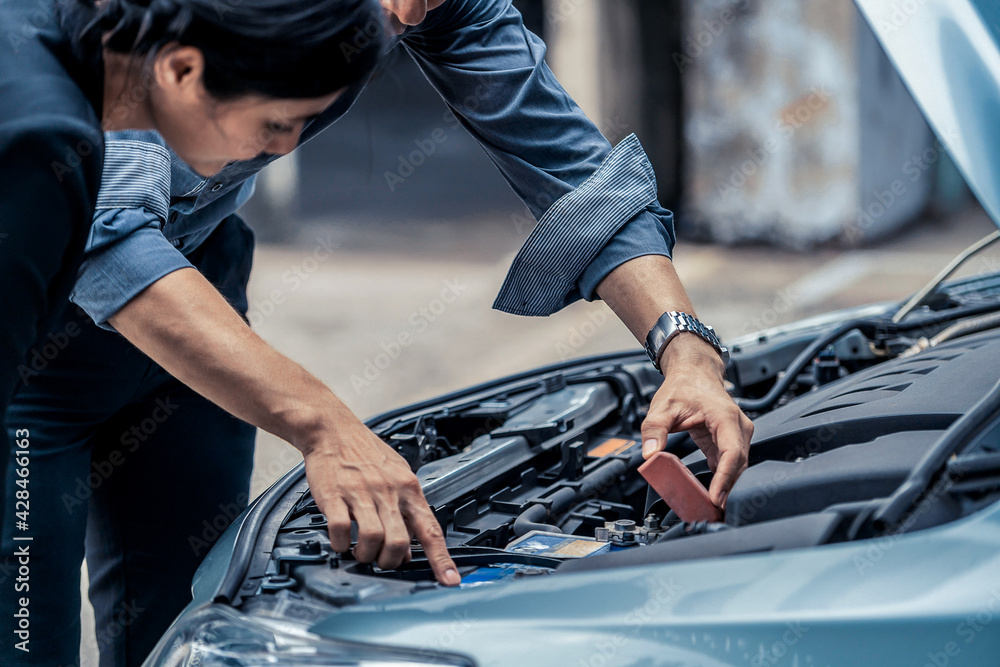 Man help woman fix the car problem. He pop up the car hood to repair ...