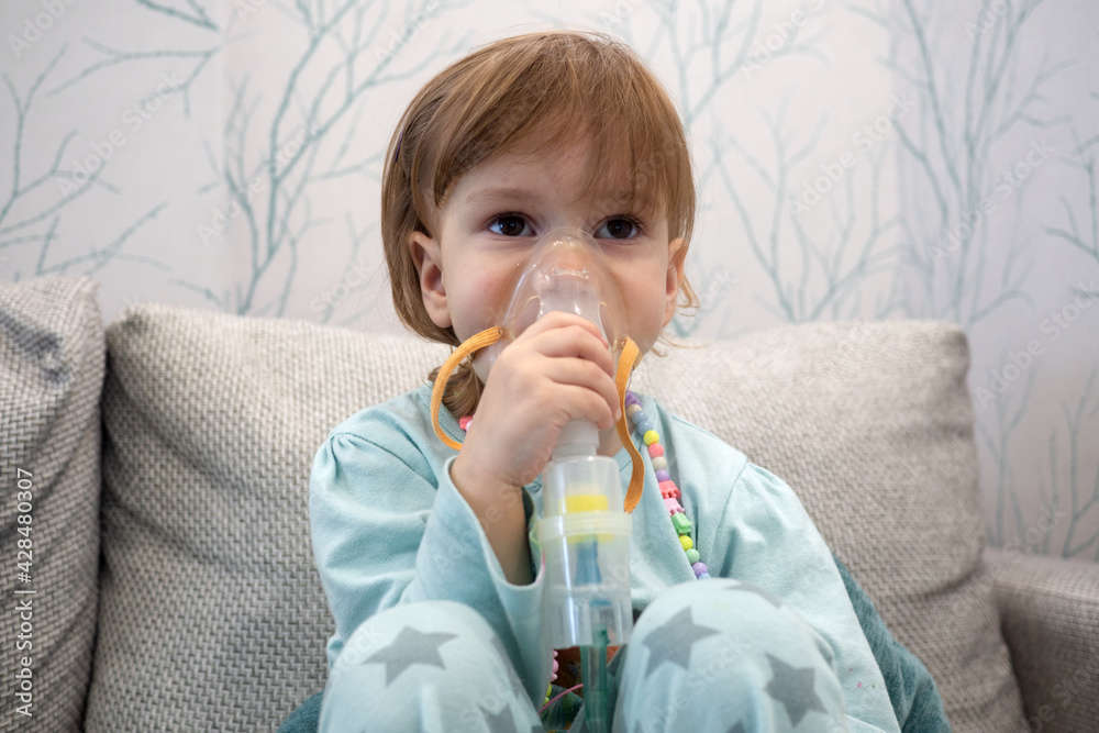 Kid girl makes inhalation with a nebulizer. sick child holding ...
