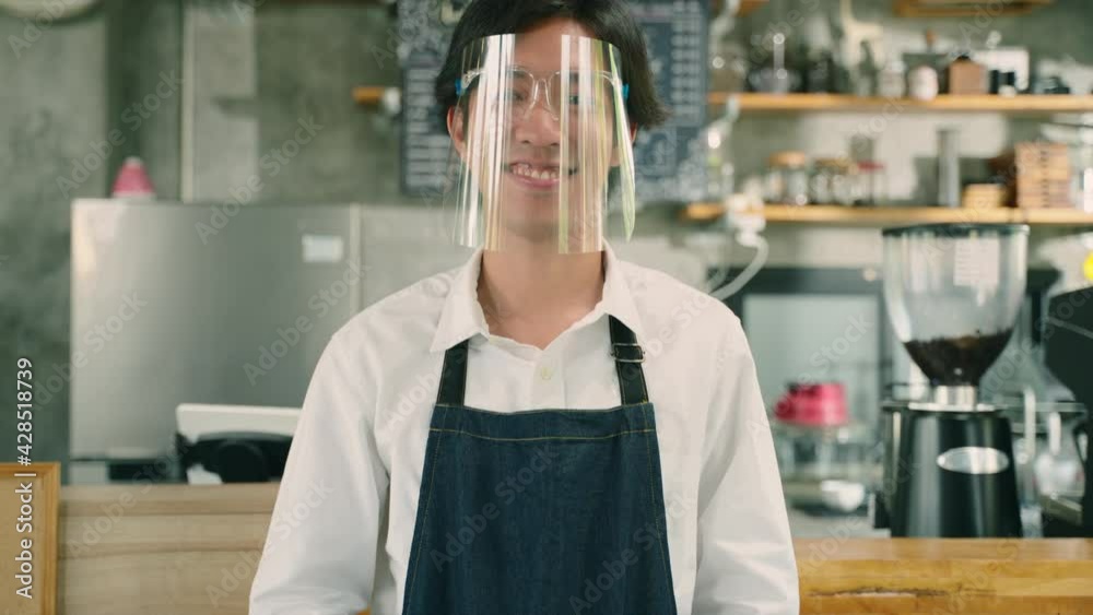 Portrait of Asian barista wearing face shield and standing in front of ...