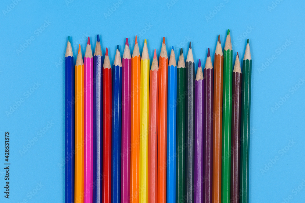 Colored pencils laid out in a row on a blue background. Stock Photo ...