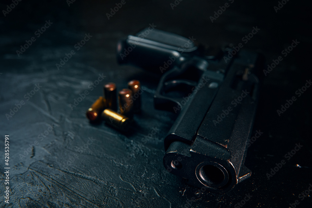 Black gun and bullets on concrete table. Firearms on dark background ...