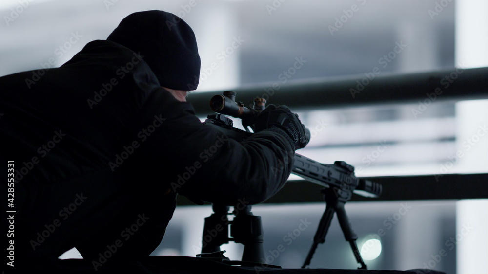 Killer adjusting sight on sniping rifle. Sniper preparing weapon for ...
