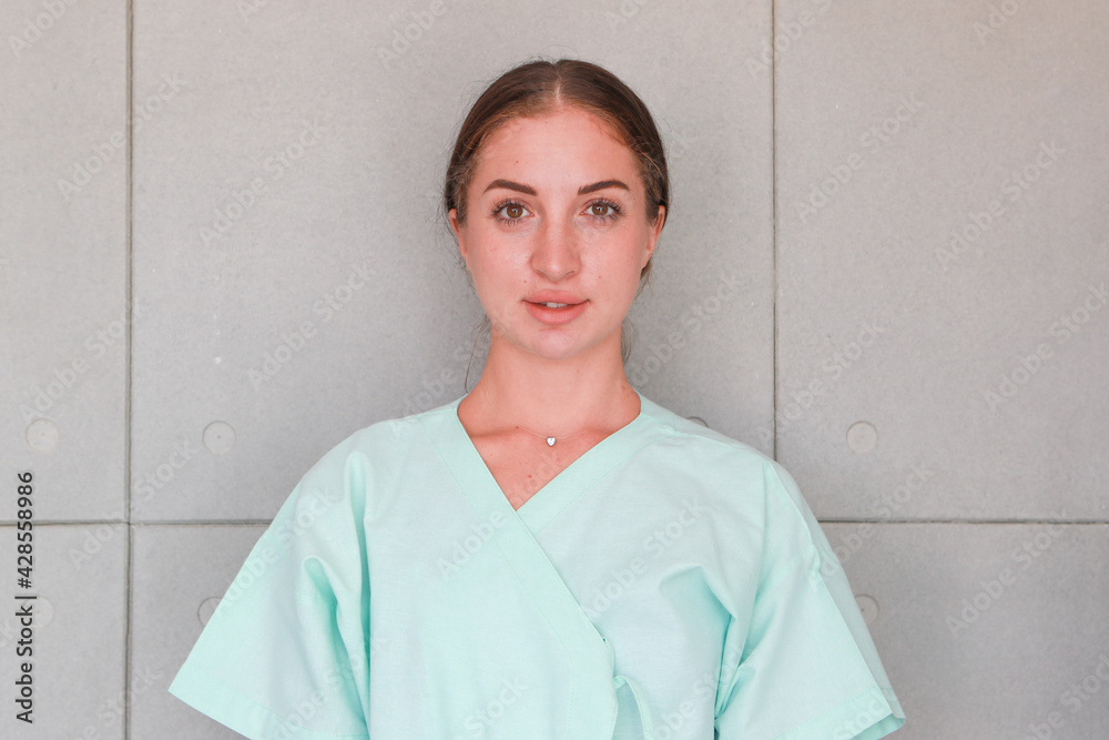 Young Caucasian female nurse with brown hair in light green hospital ...