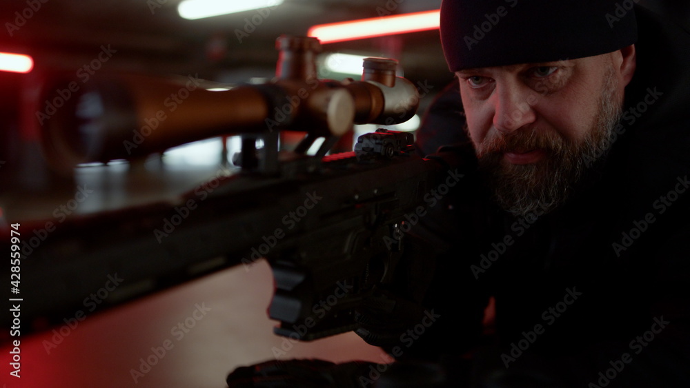 Killer looking aim with binoculars. Serious man targeting scope on ...