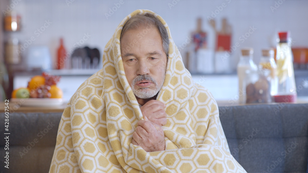 The old man, sitting in his cold house with a blanket wrapped, trembles ...