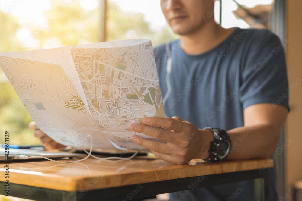Traveler using a map to locate the destination. Man sitting and looking ...