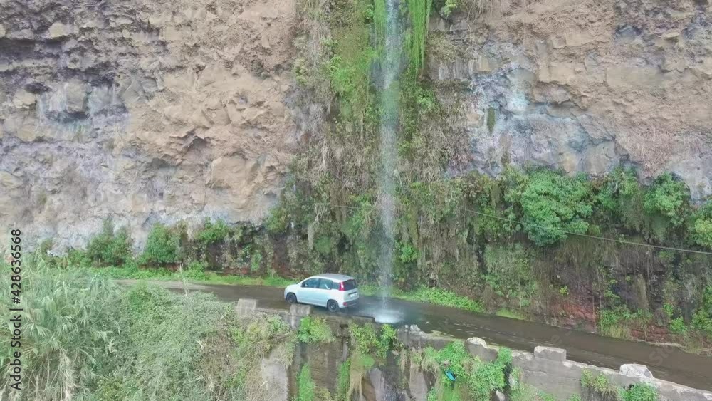 Unidentifiable automobile drives under a misty waterfall known as ...