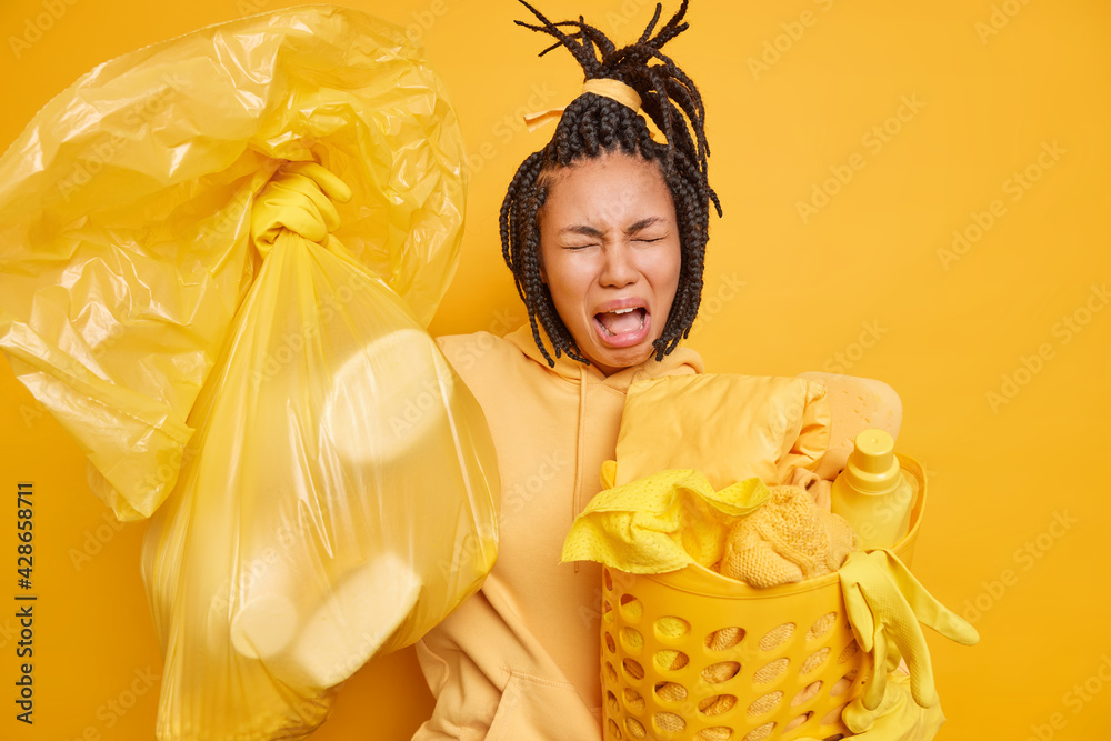 Dejected frustrated woman removes rubbish and dirt from house takes out ...